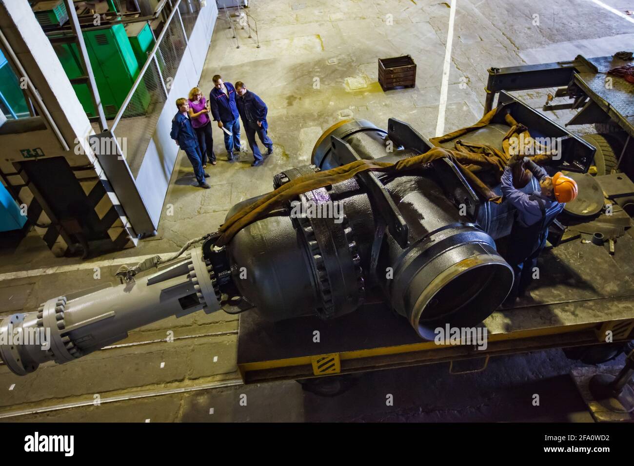 Worker lifts giant shut-off valve by mobile crane.Loading on rail ...