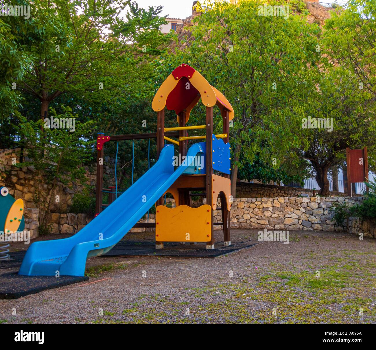 Blue slide in a children's playground with lovely green trees and low ...