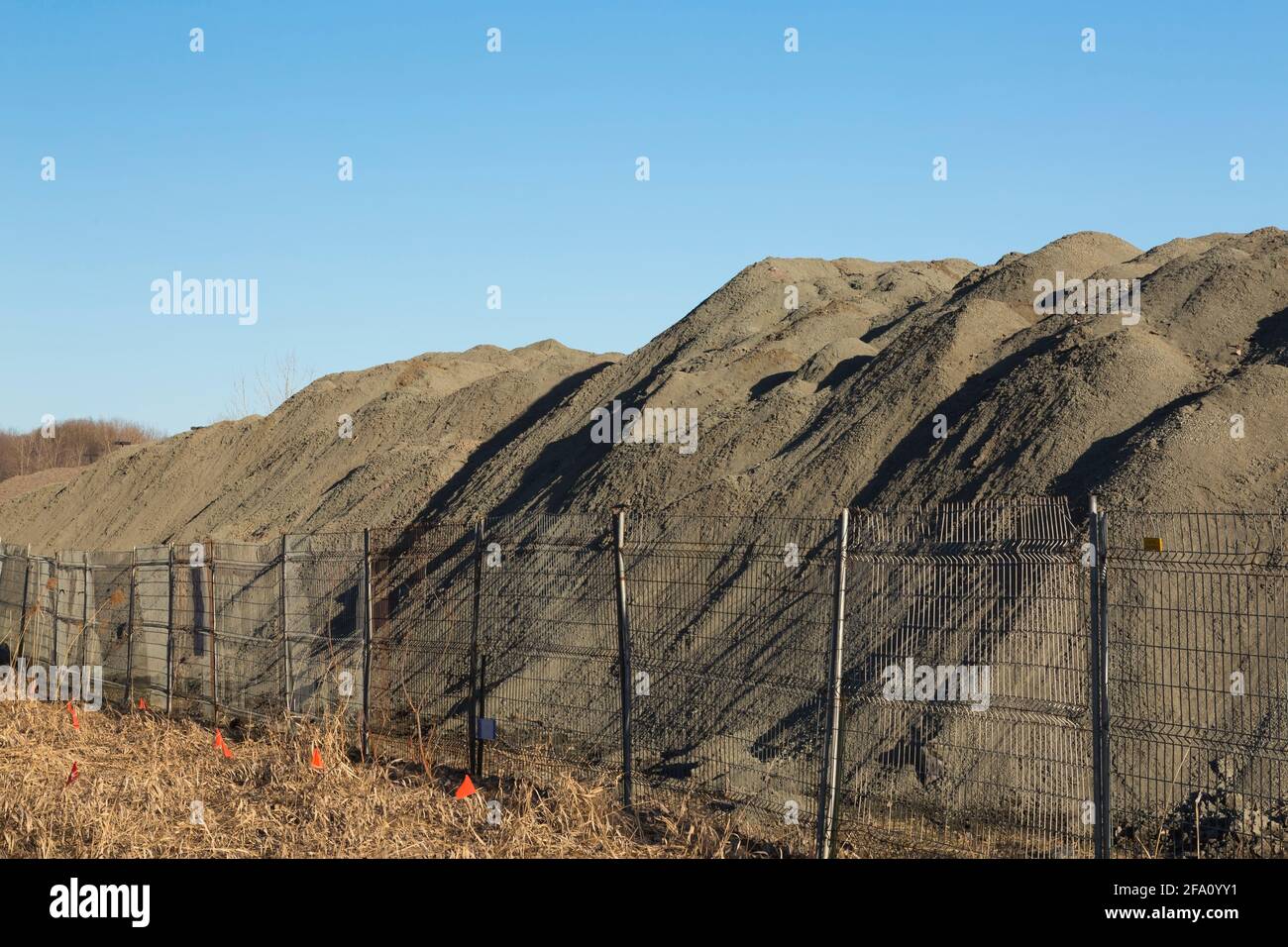 Security fence guarding piles of excavated earth at construction site ...