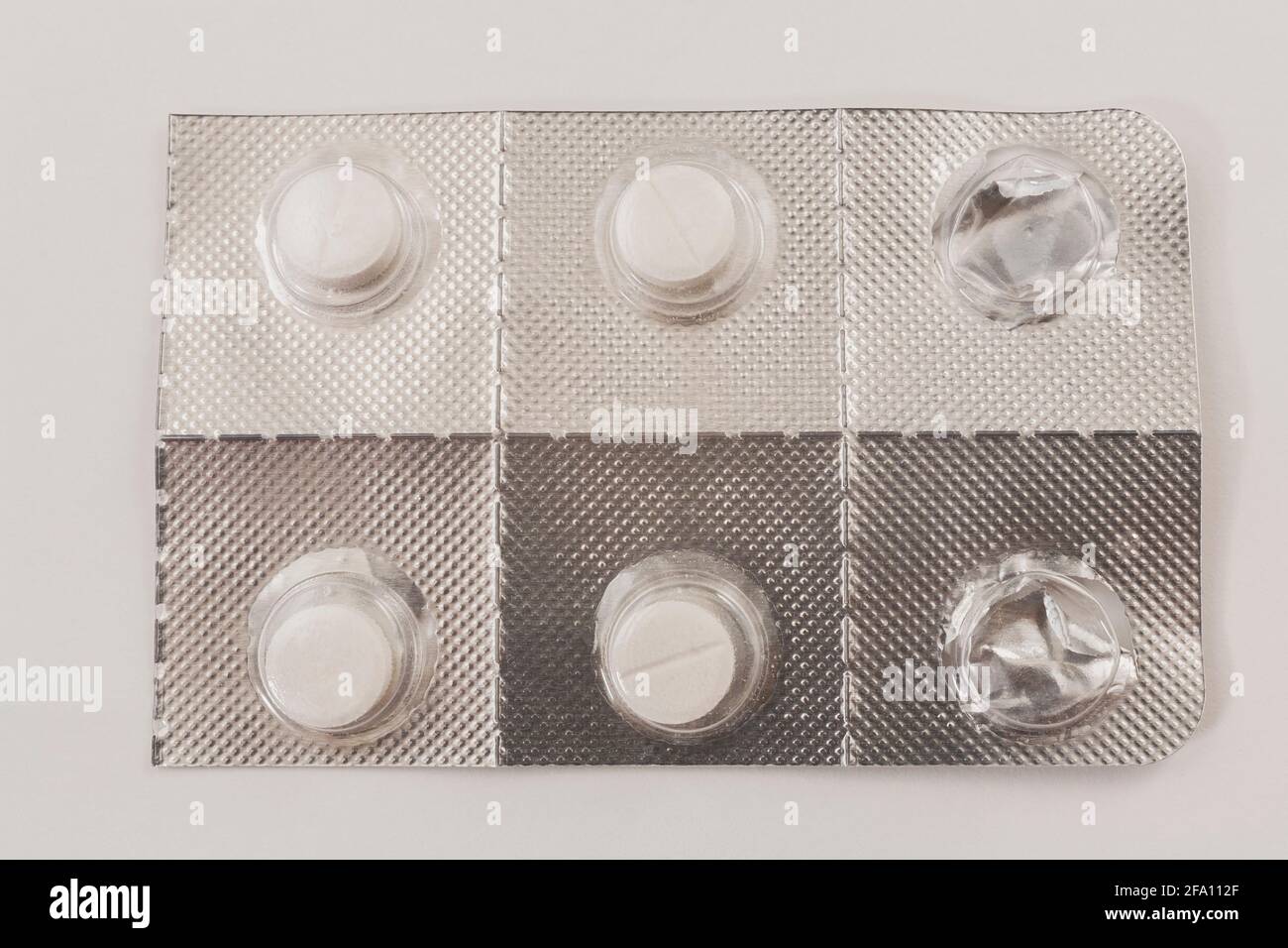 White medicine pills missing in silver packaging on top of white ...