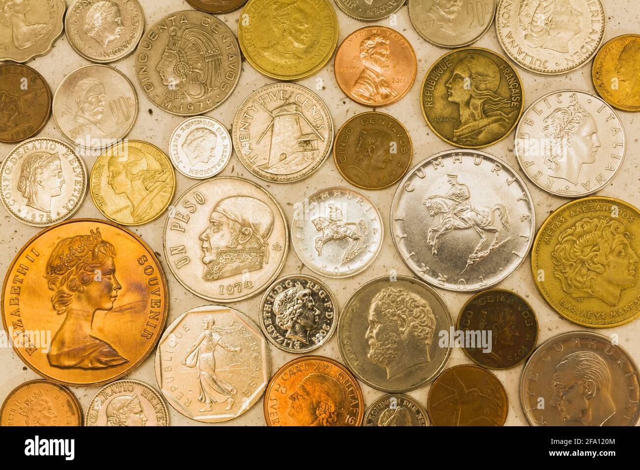 Foreign coins on white speckled background Stock Photo - Alamy