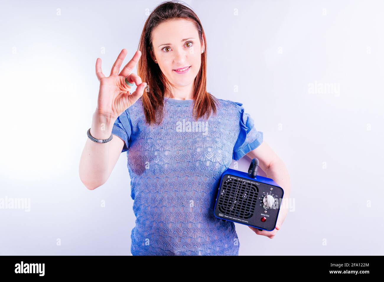 beautiful young woman holding an ozone generating machine making ok ...