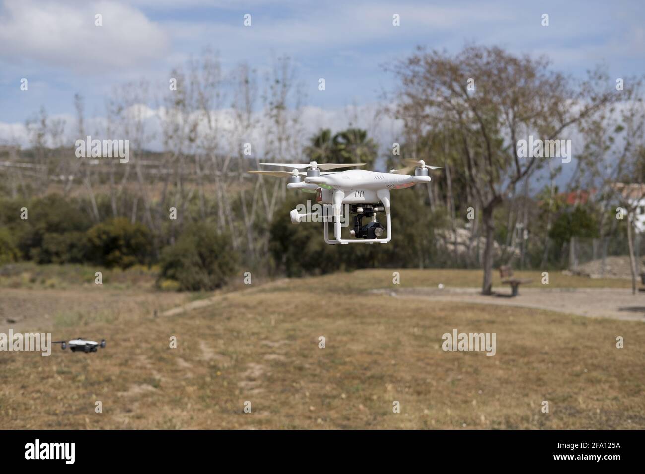 Two drones flying over the field under a cloudy sky during a flight ...