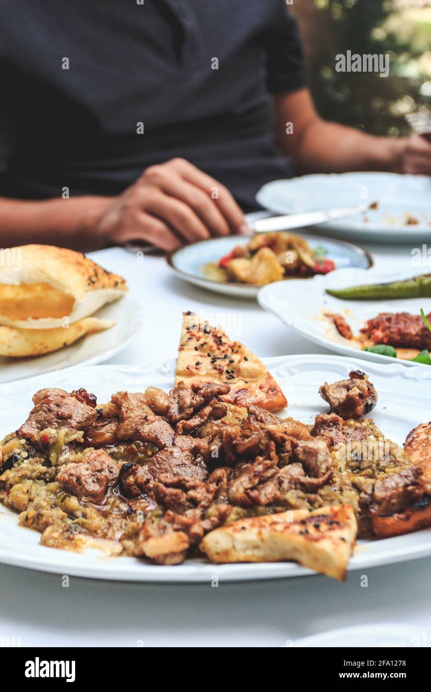 Vertical shot of people at the table eating a dish with meat Stock ...