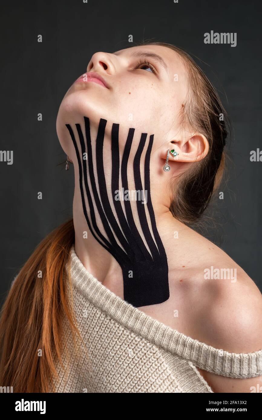 Kinesiology tape placed on the neck of a young caucasian teenager girl ...