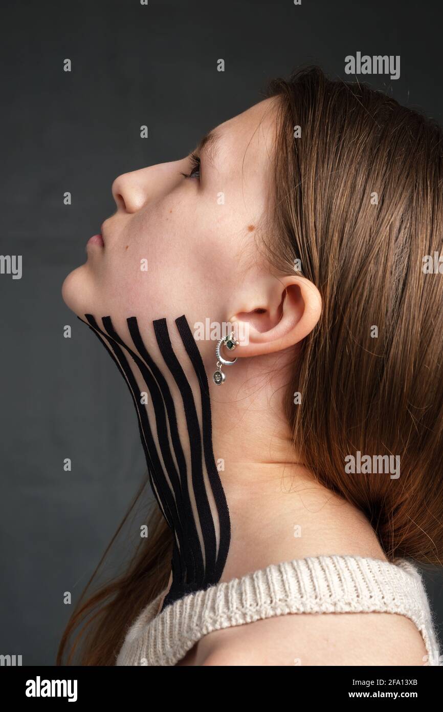 Kinesiology tape placed on the neck of a young caucasian teenager girl ...