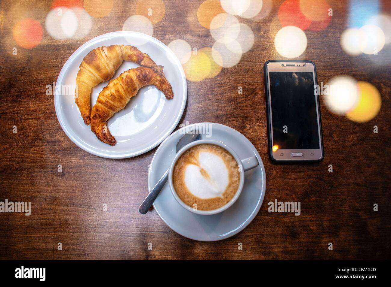 Latte coffee with fat croissants and cell phone Stock Photo - Alamy