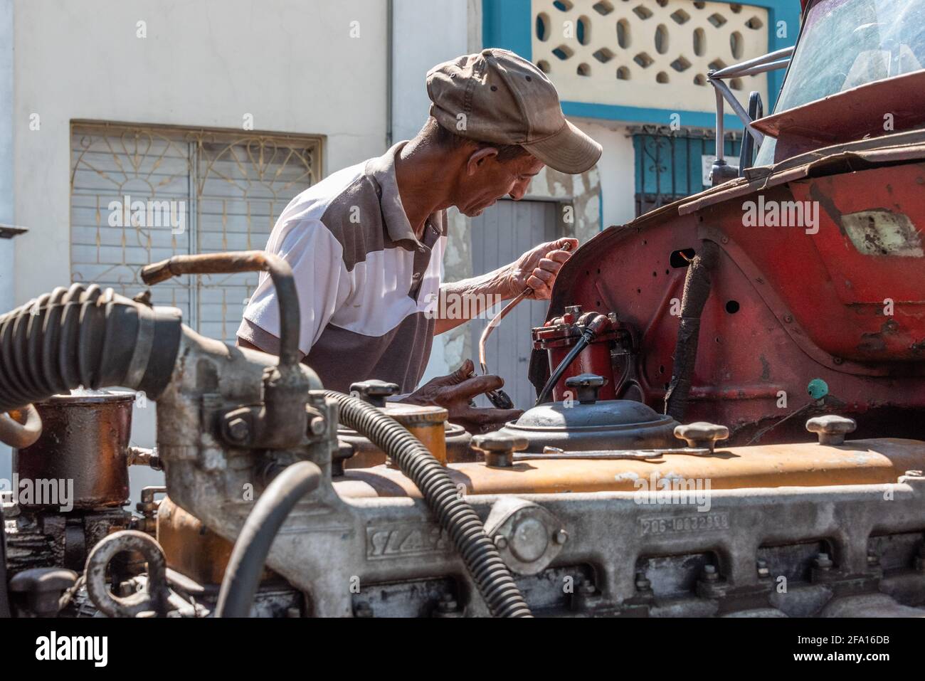 Cuban driver repairing a broken truck on a city street, Santiago de ...