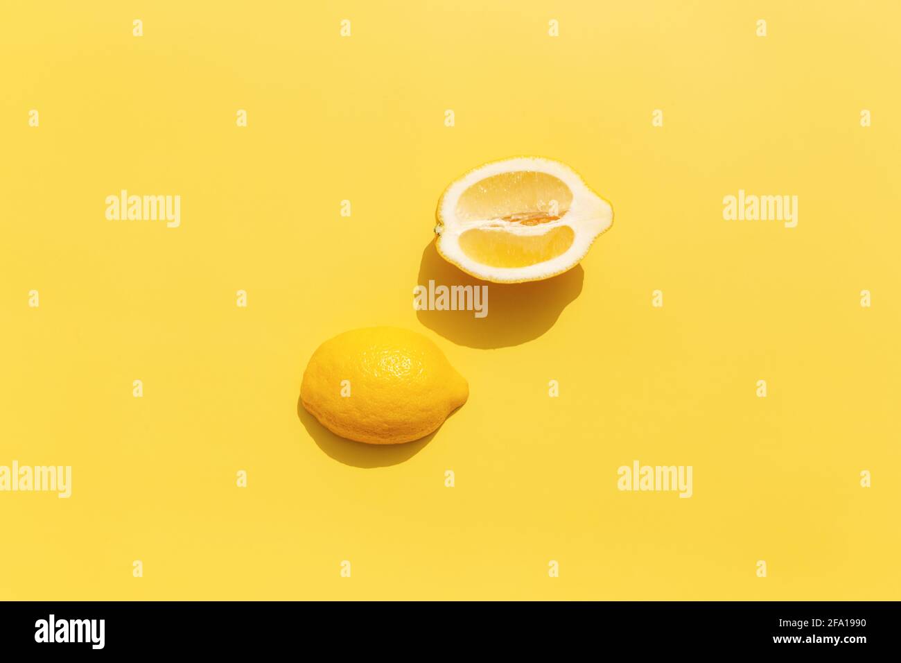 Two halved cuts of lemon with shadow on yellow background. Healthy ...