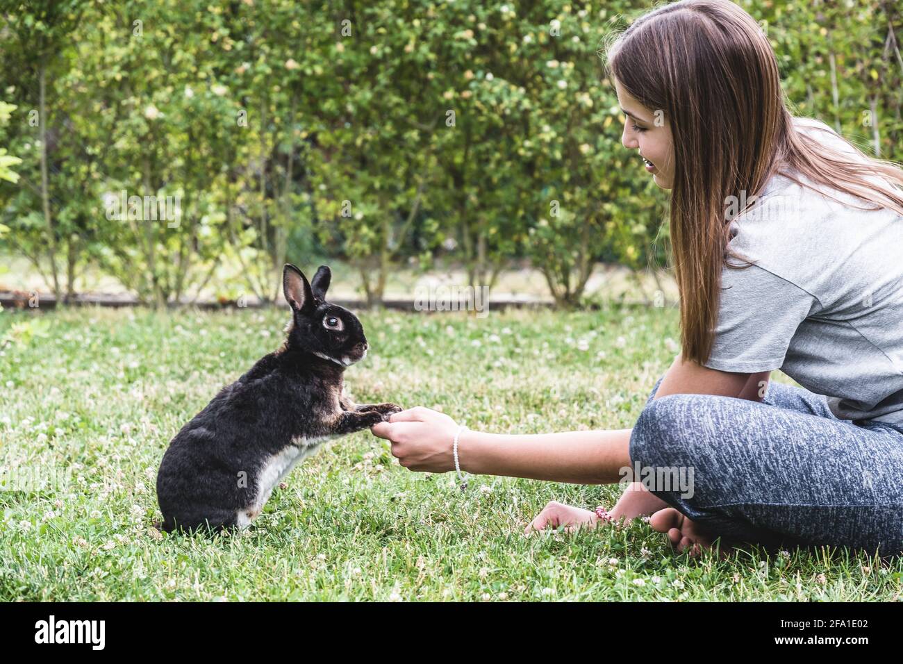 Teenager girl playing with her black rabbit in the garden Stock Photo ...