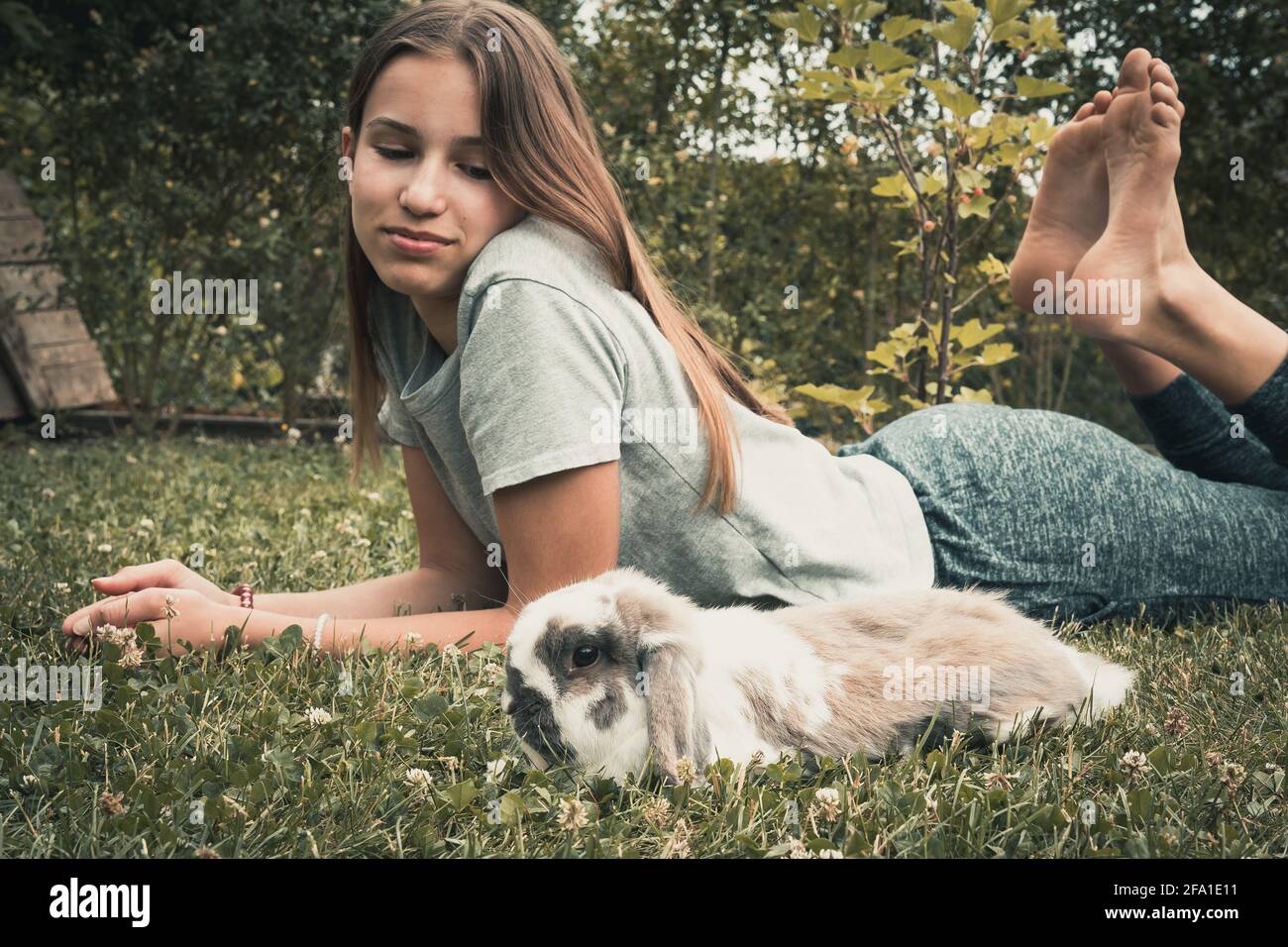 Teenager girl and her rabbit lying in the green grass Stock Photo - Alamy