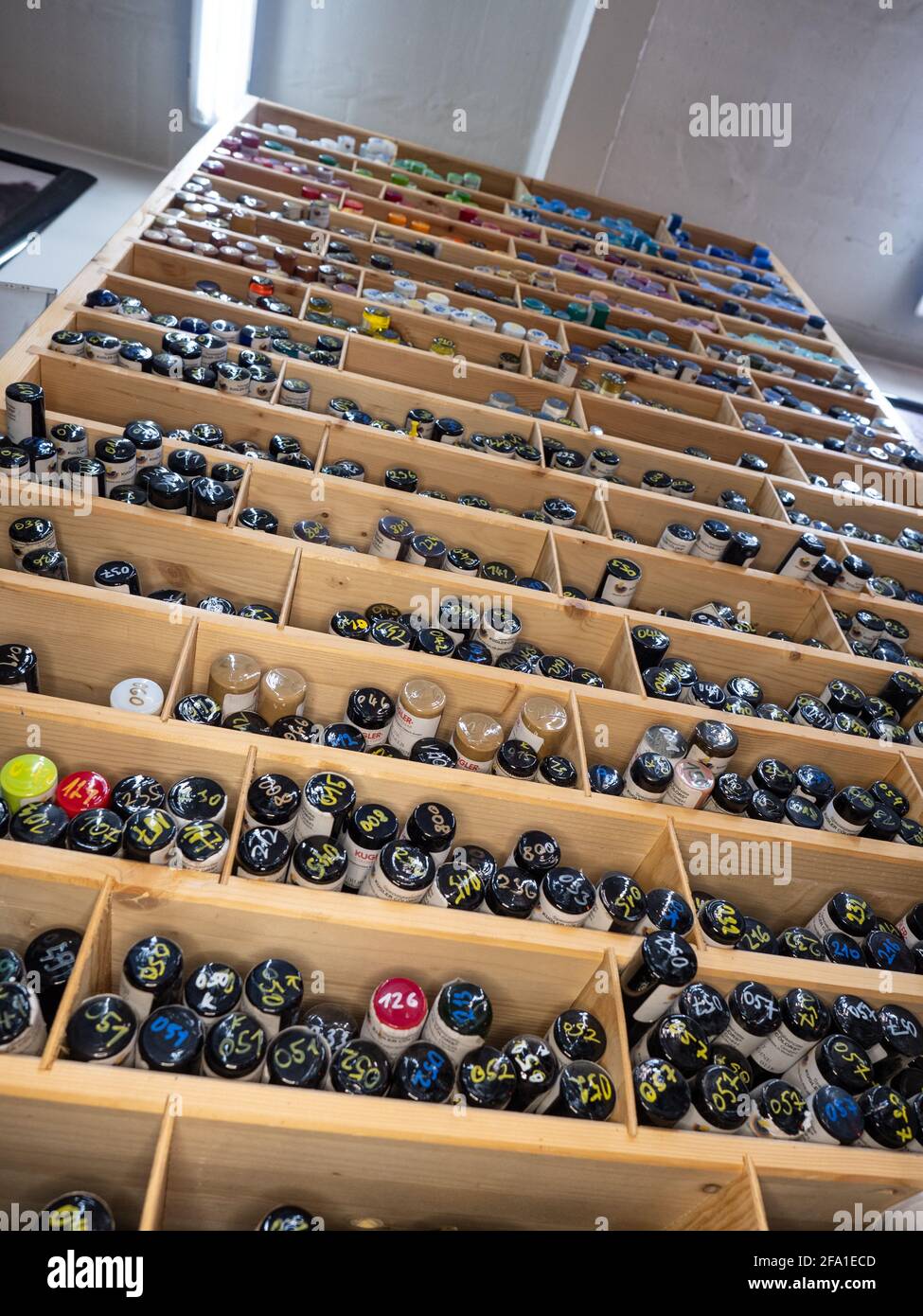 Color glass bars in wooden rack. Bunch of colorful glass rods on shelf ...