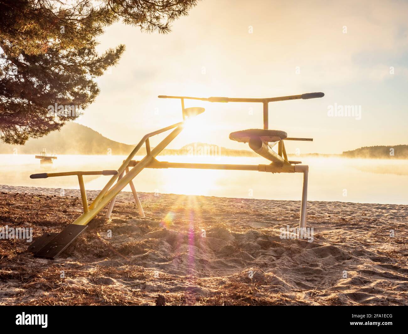 Colorful sunset with seesaw on beach. Teeter totter with wooden chairs ...