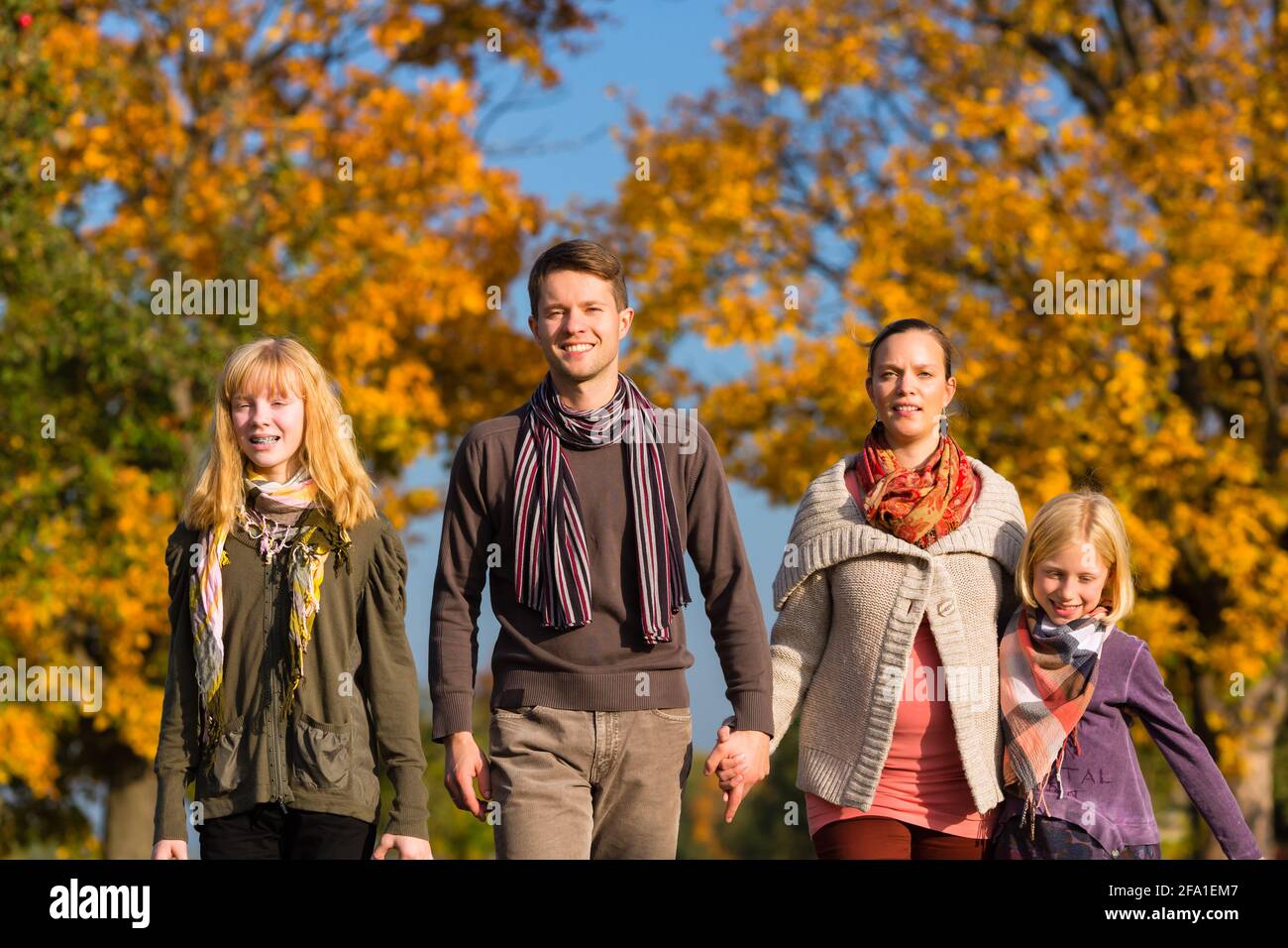 Young family with Mother, father and daughters walking through colorful ...