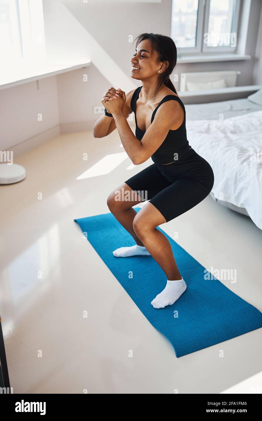 Cheerful young woman doing exercise at home Stock Photo - Alamy