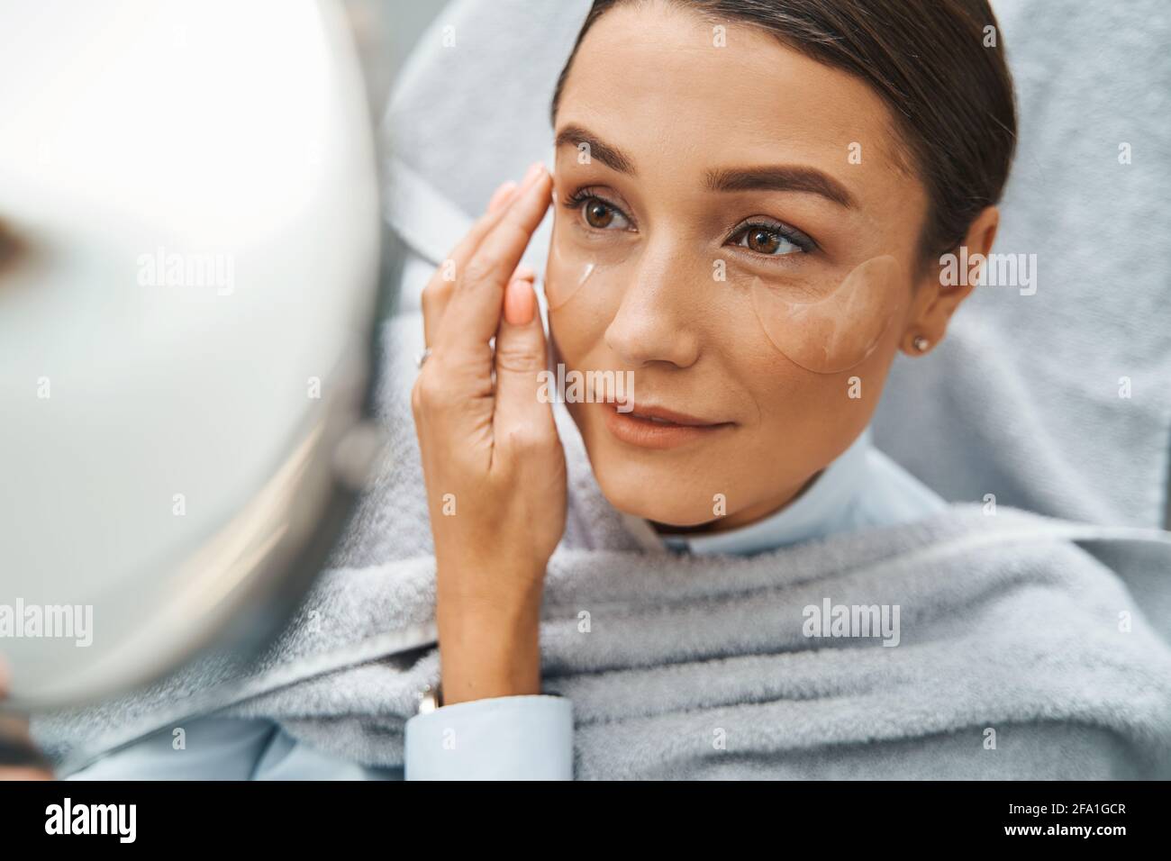 Young beauty salon customer viewing her reflection using a handglass ...