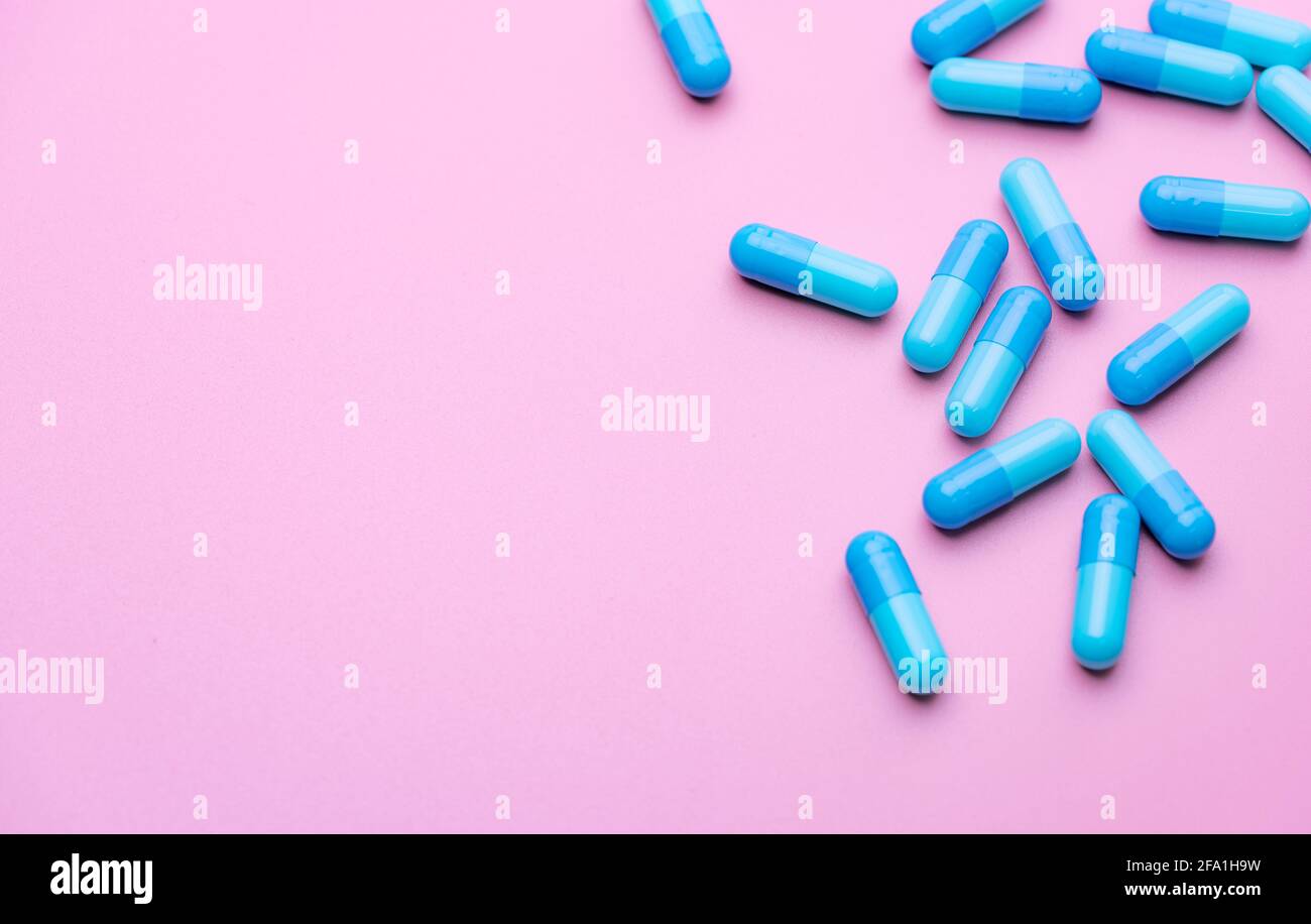 Blue capsule pills on pink background. Blue capsule pills with copy ...