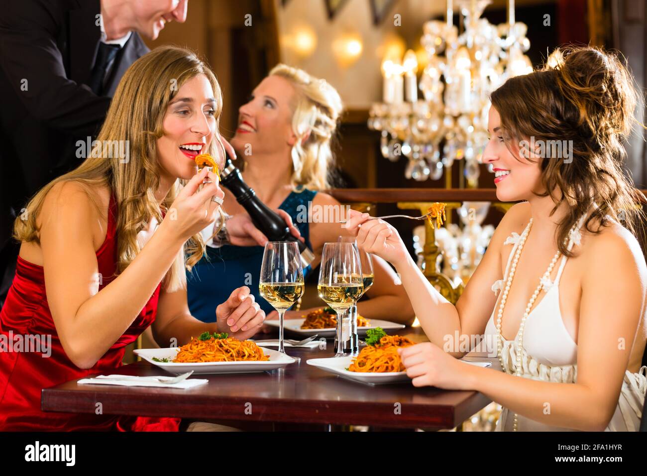 Good friends for lunch in a fine restaurant, waiter spices the dinner ...