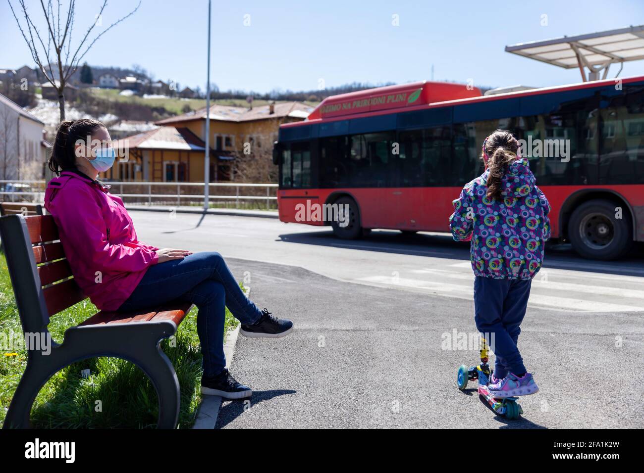 A young mother with a female child at a bus stop Stock Photo - Alamy