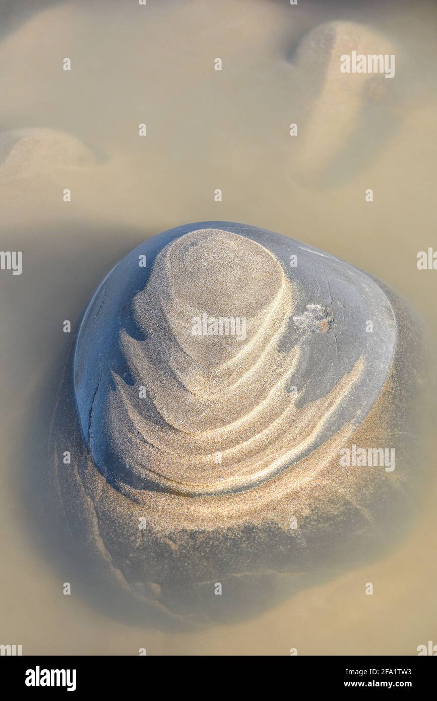 Sand forms abstract shape on the rocks as the tide goes out Stock Photo ...