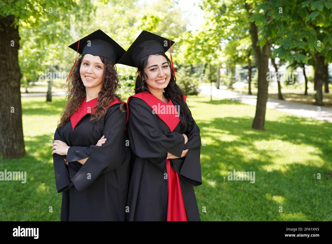 Portrait of successful graduate female students wearing cap outdoors ...