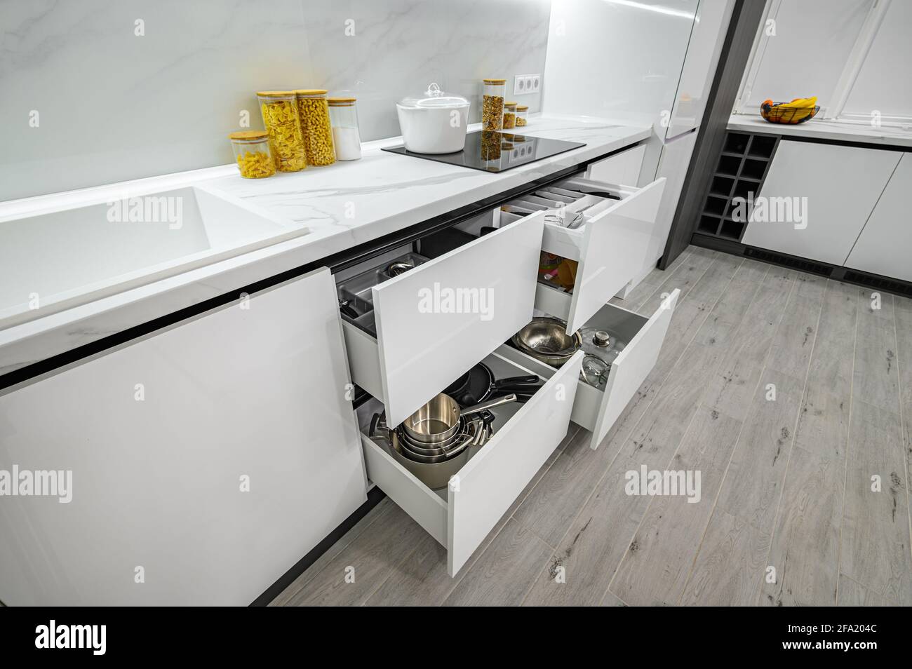 Luxurious white and black modern kitchen interior, drawers pulled out ...