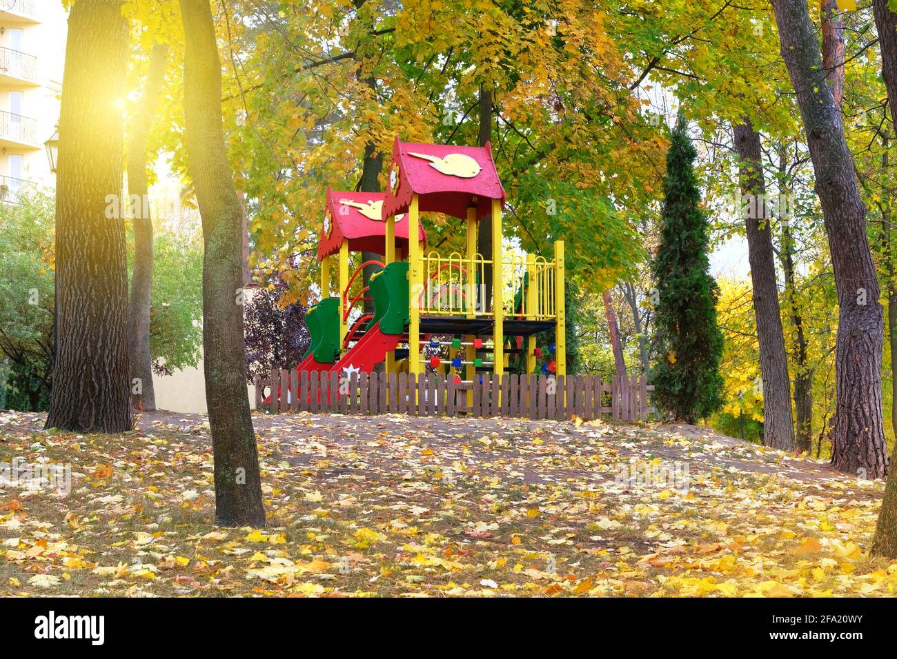 Children playground surrounded by yellow trees in sunlight in autumn ...