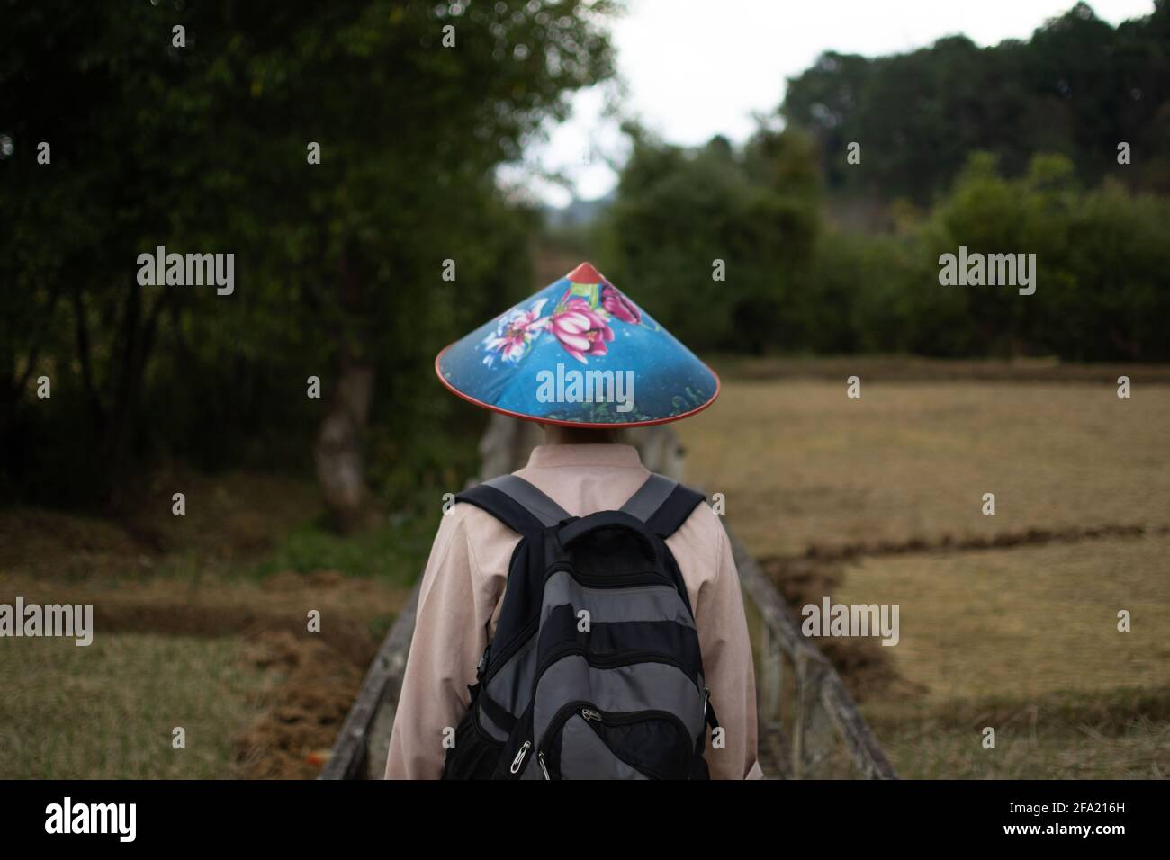 A burmese man in traditional clothing and a colorful blue hat trekking ...