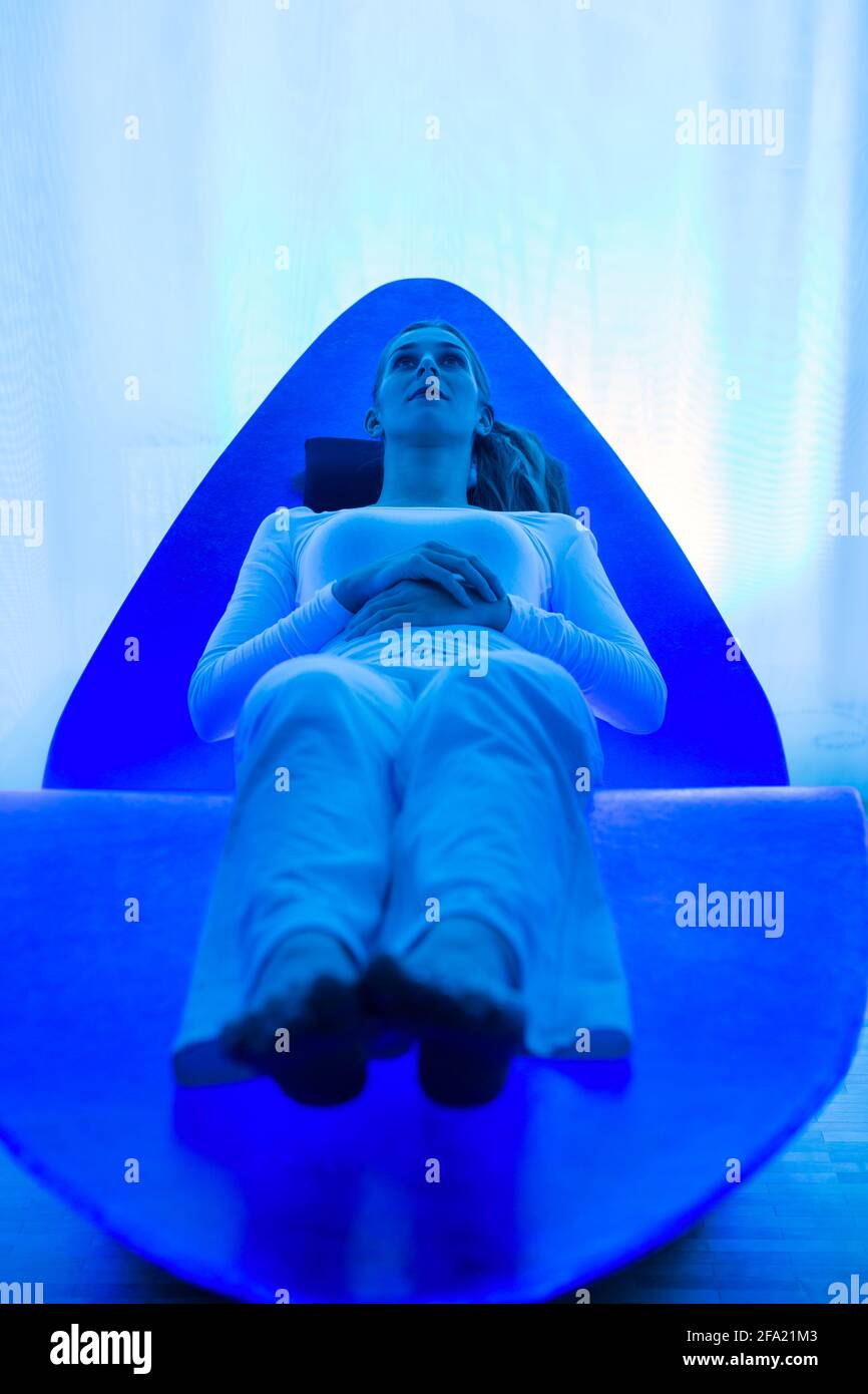 Woman enjoying alpha therapy in spa, colorful lights stimulating the ...