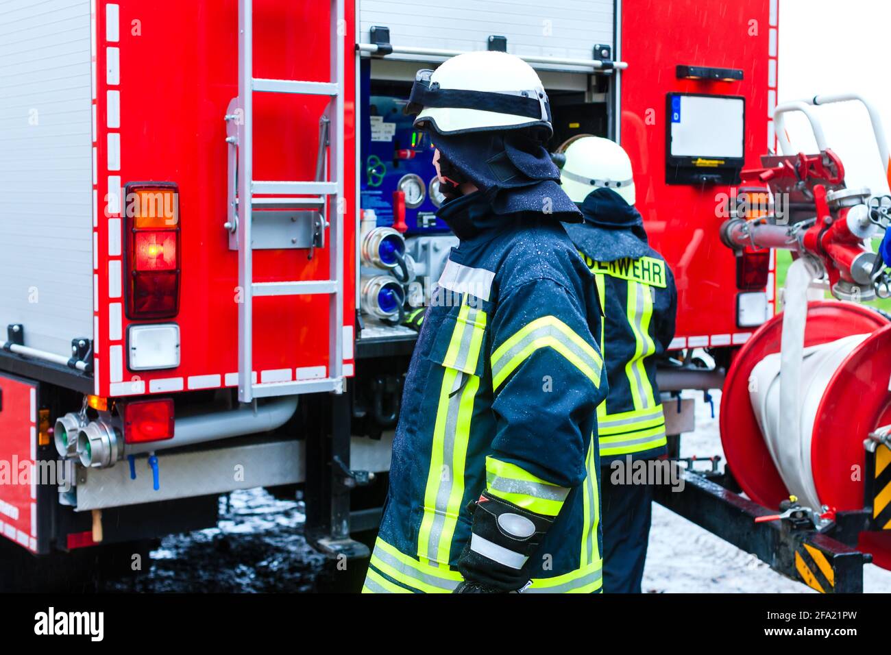 young fireman in uniform standing in front of firetruck, he is ready ...
