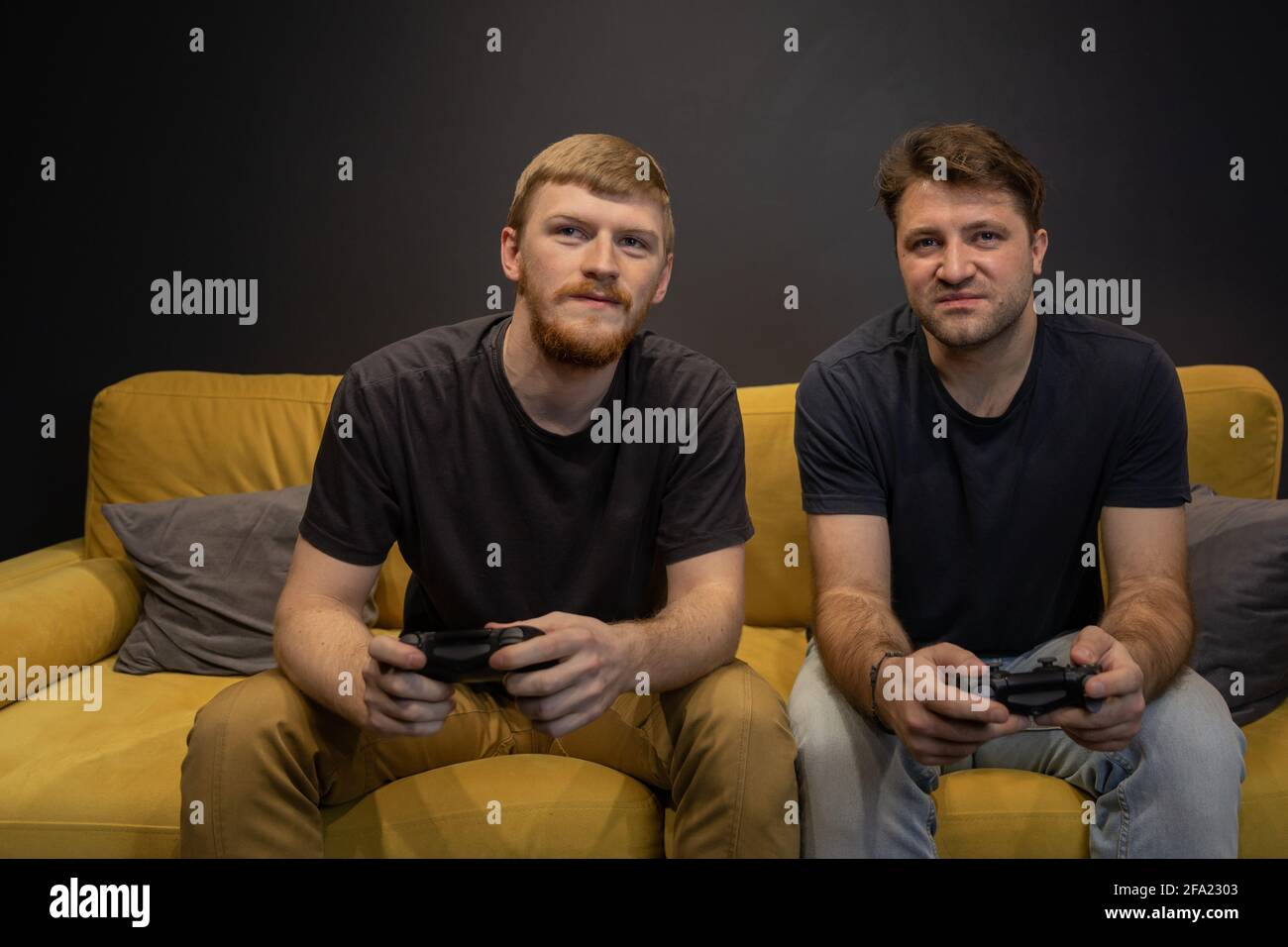 two cheerful handsome guys play passionately video game holding console ...