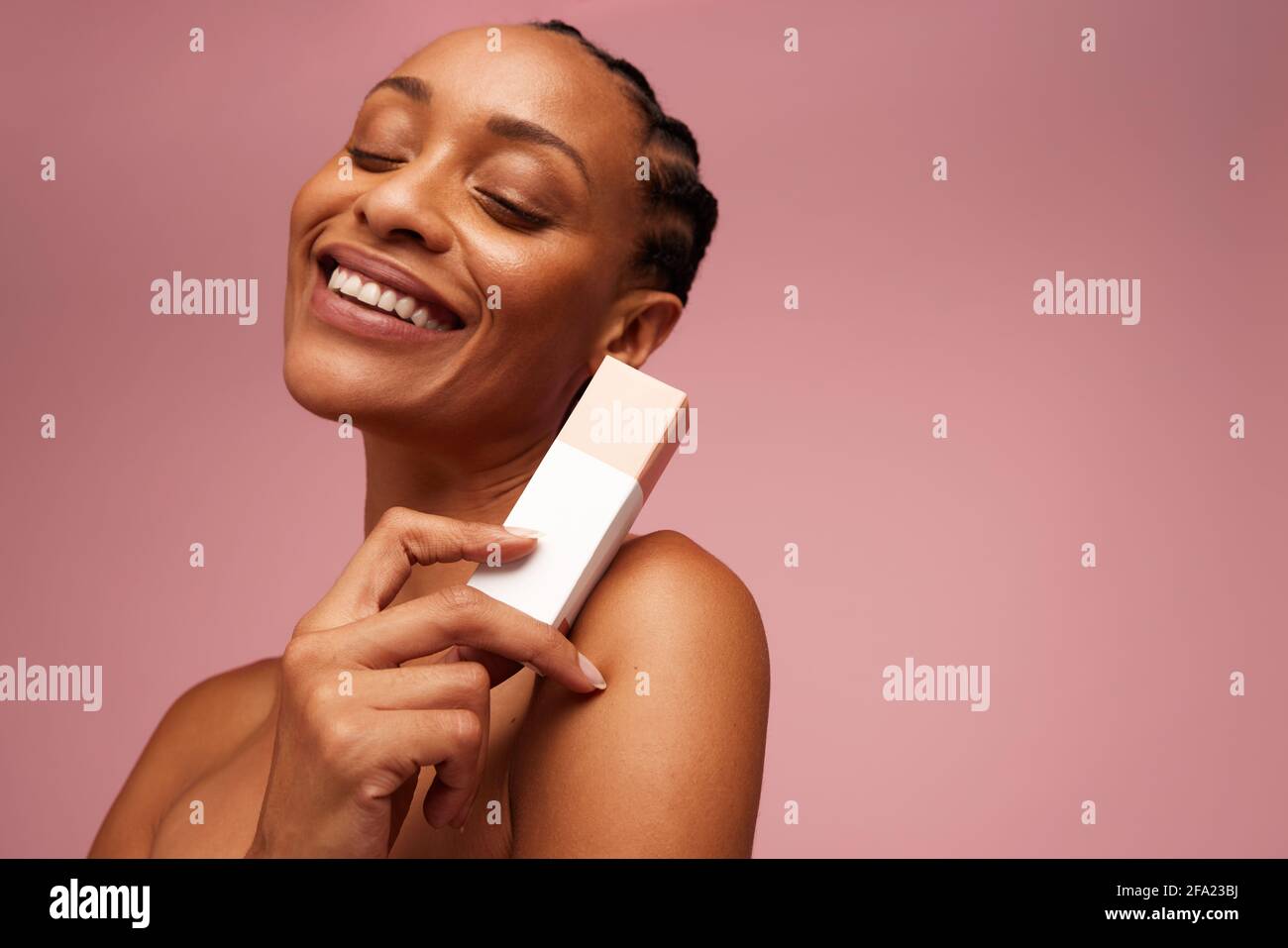 Portrait of a happy woman holding cosmetic product and smiling ...