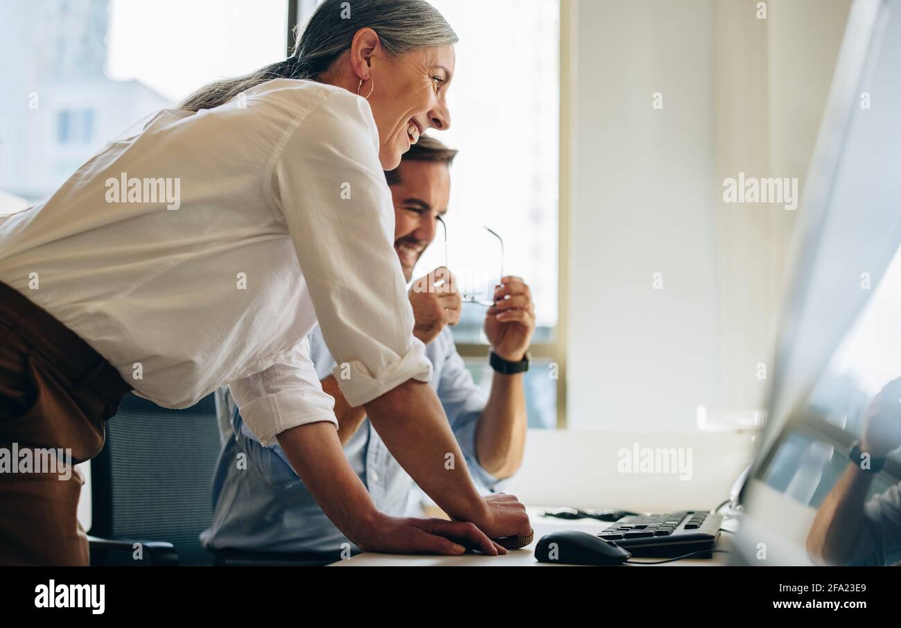 Female manager with coworker checking status of project on computer ...