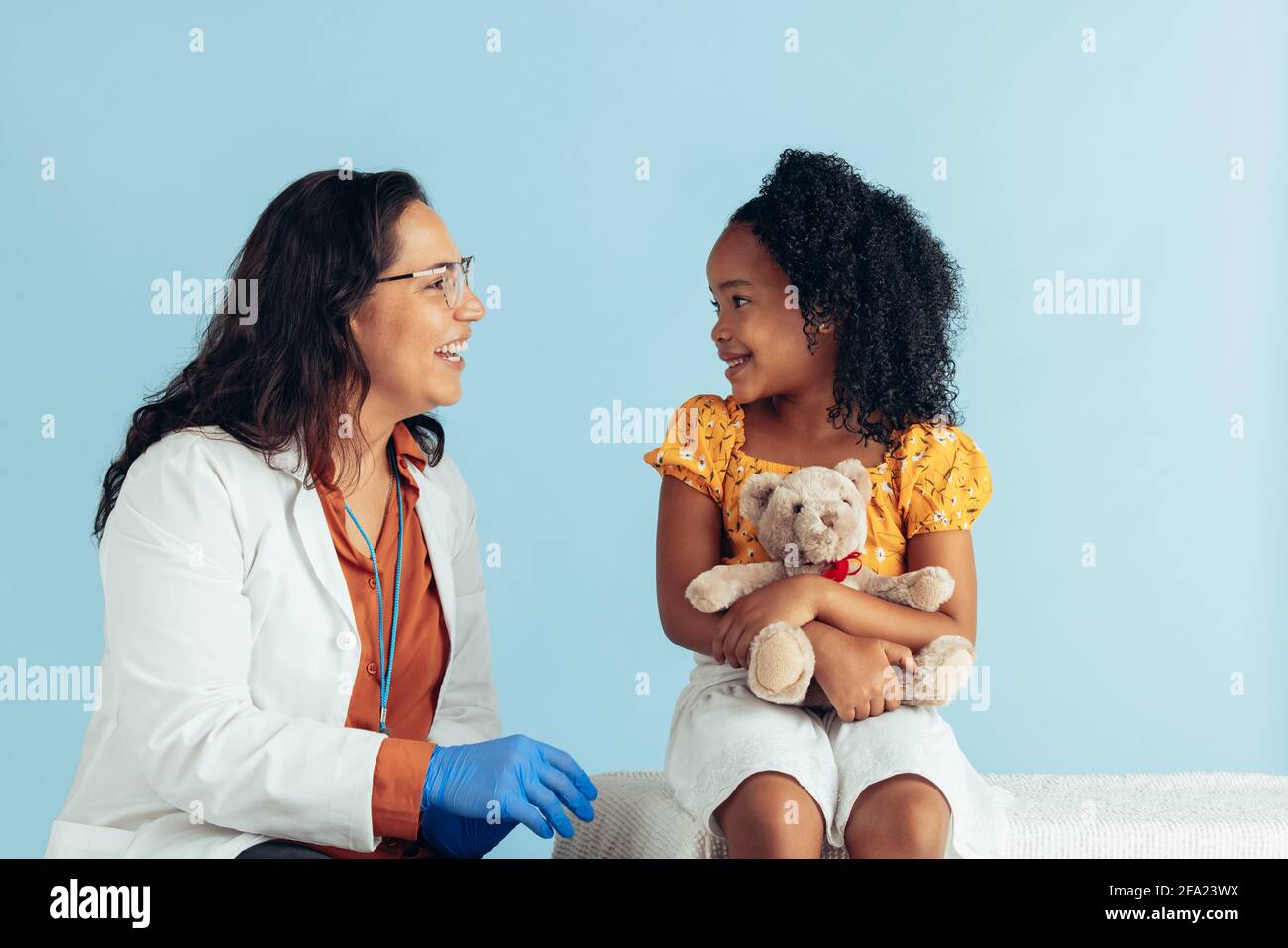 Doctor and girl smiling on blue background. Smiling pediatrician ...