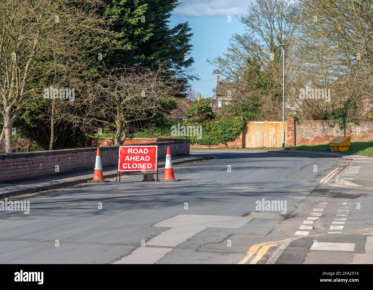 Red and white road closure sign with two red and white traffic cones in ...