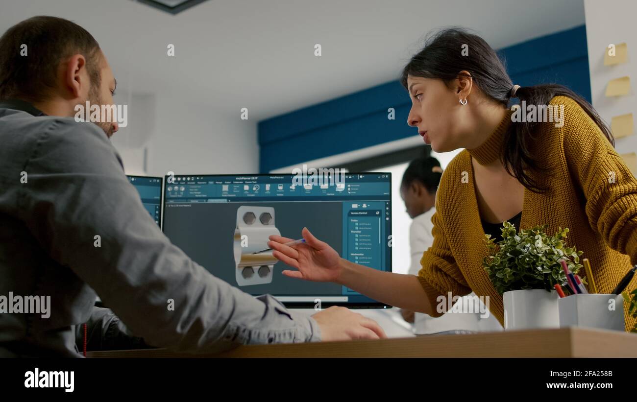 Industrial designer discussing with colleague while working in CAD ...