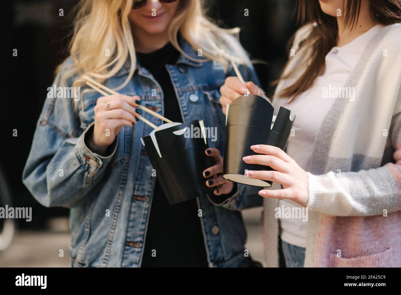 Female friends buy asian food. Girls open boxes and use food sticks ...