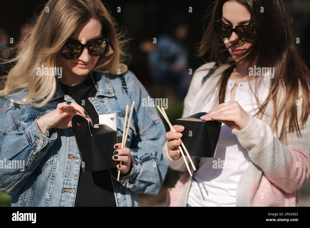 Female friends buy asian food. Girls open boxes and use food sticks ...