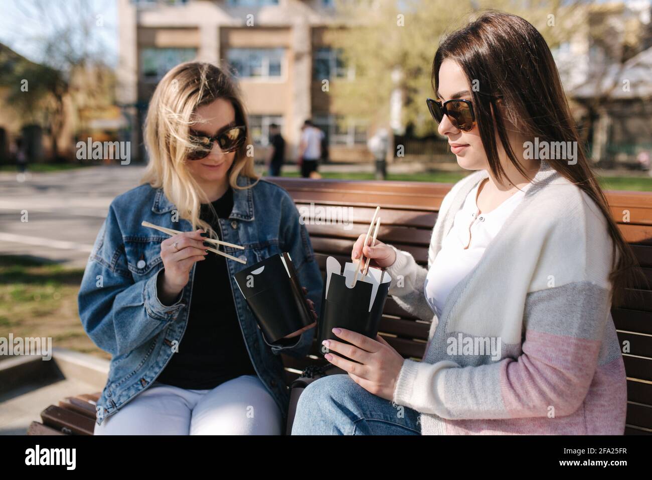 Two pretty woman eating fastfood oudtood. Beautiful girl sitting on ...