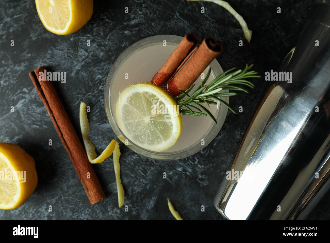 Glass of lemonade with cinnamon and rosemary on black smokey table ...
