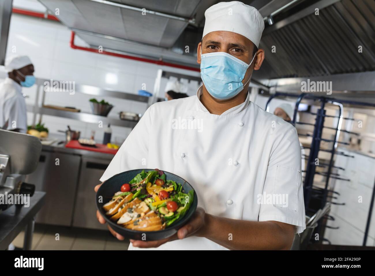 Portrait of mixed race male professional chef with finished dish ...