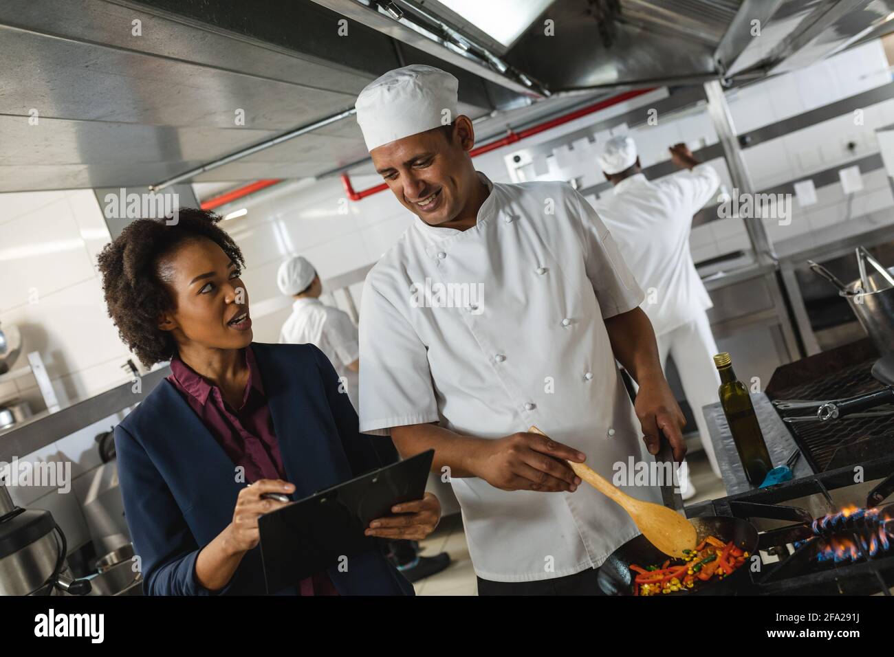 Diverse race female kitchen manager discussing with professional chef ...