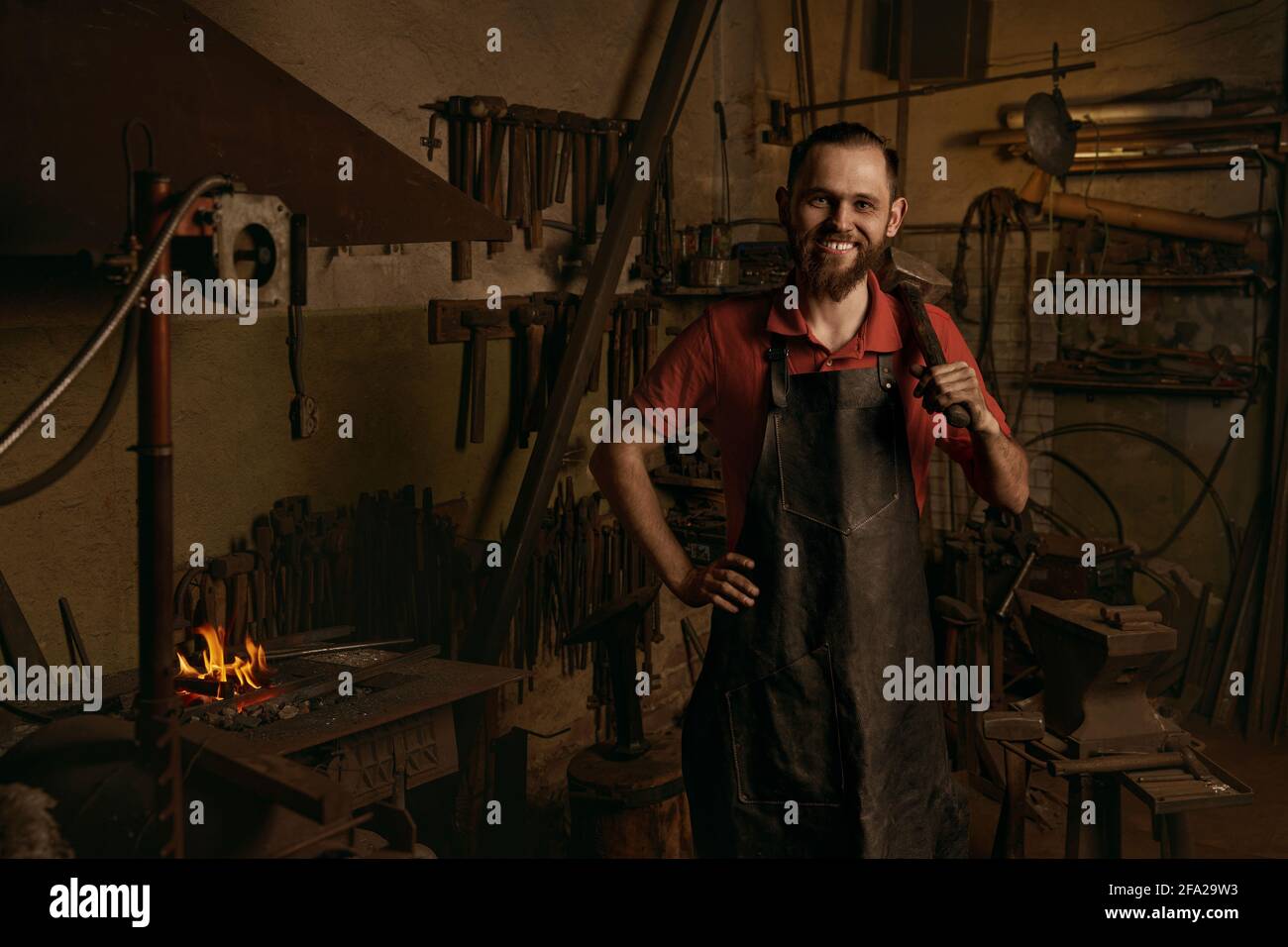 Blacksmith with hammer in workshop portrait smiling Stock Photo - Alamy