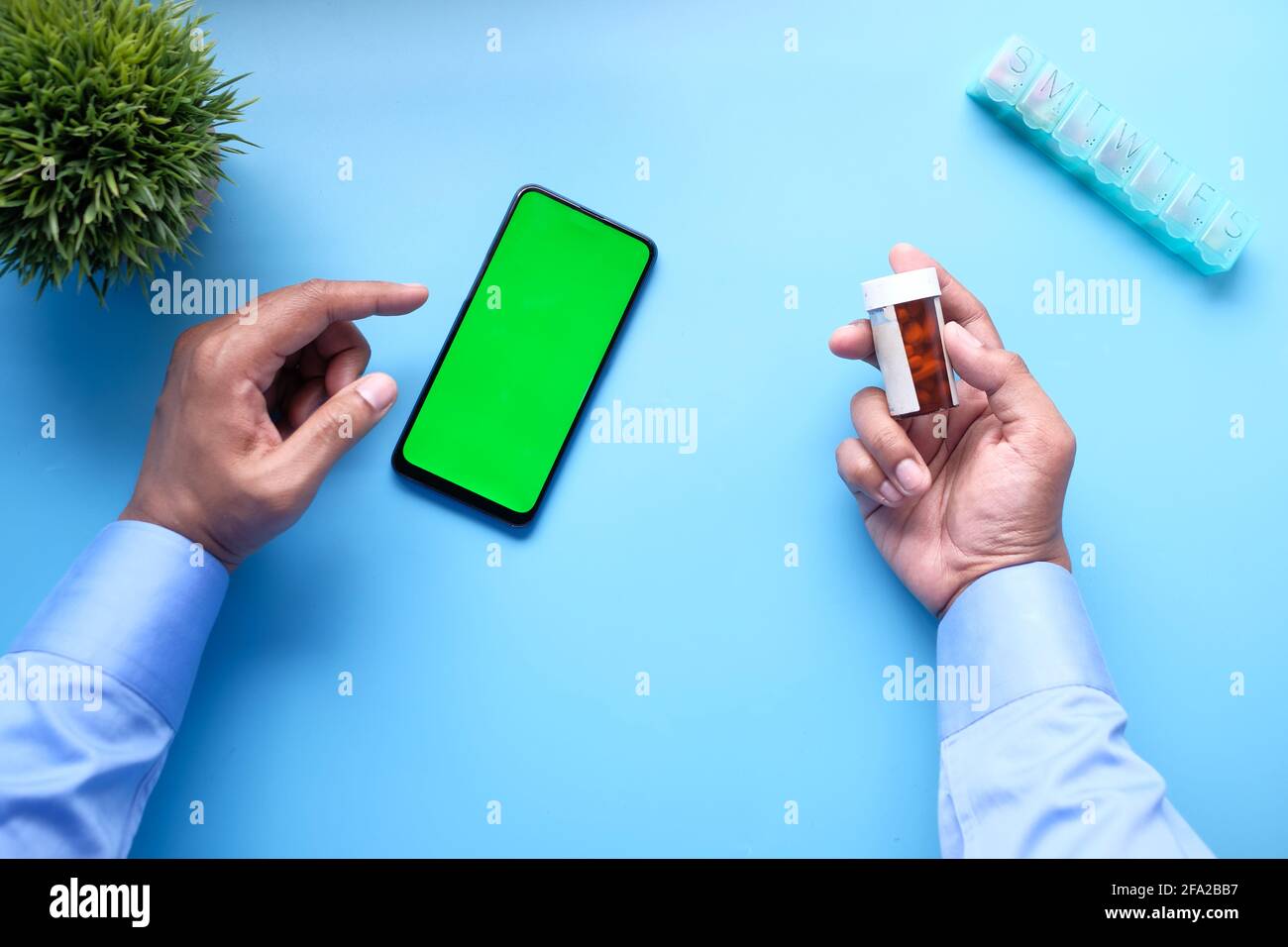 top view of young man hand using smart phone and holding a pill ...