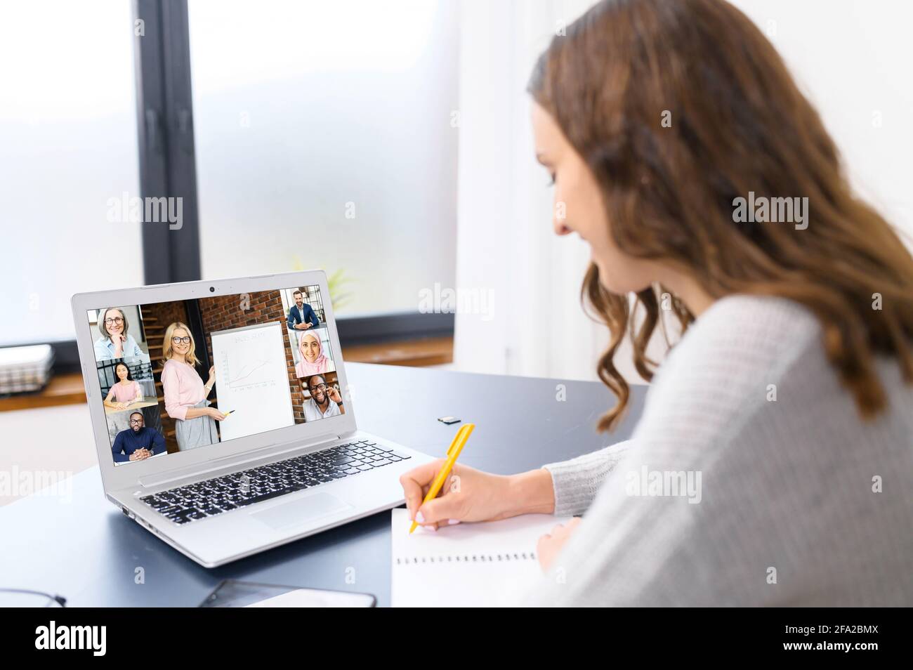 Female student studying online, watching webinar holding female teacher ...