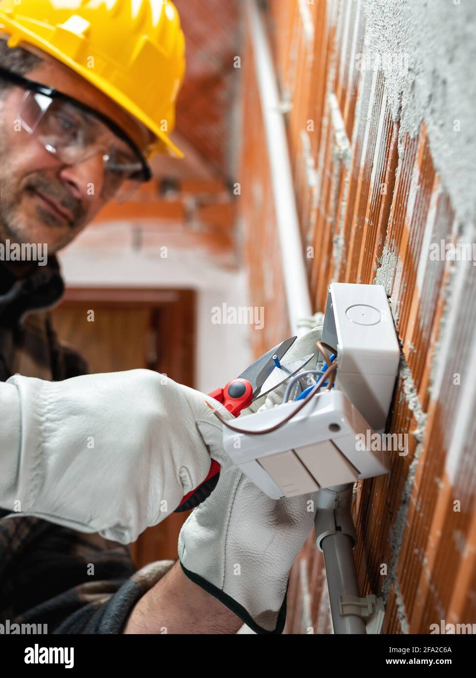 Electrician worker with scissors prepares the electrical cables of an ...