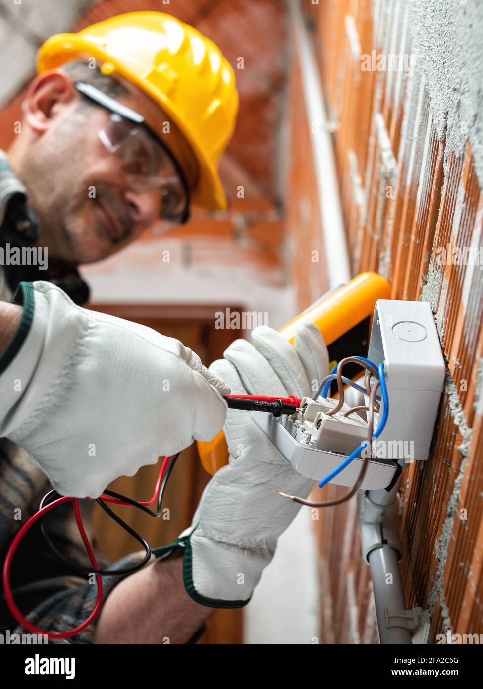 Electrician worker with tester measures the voltage in an electrical ...