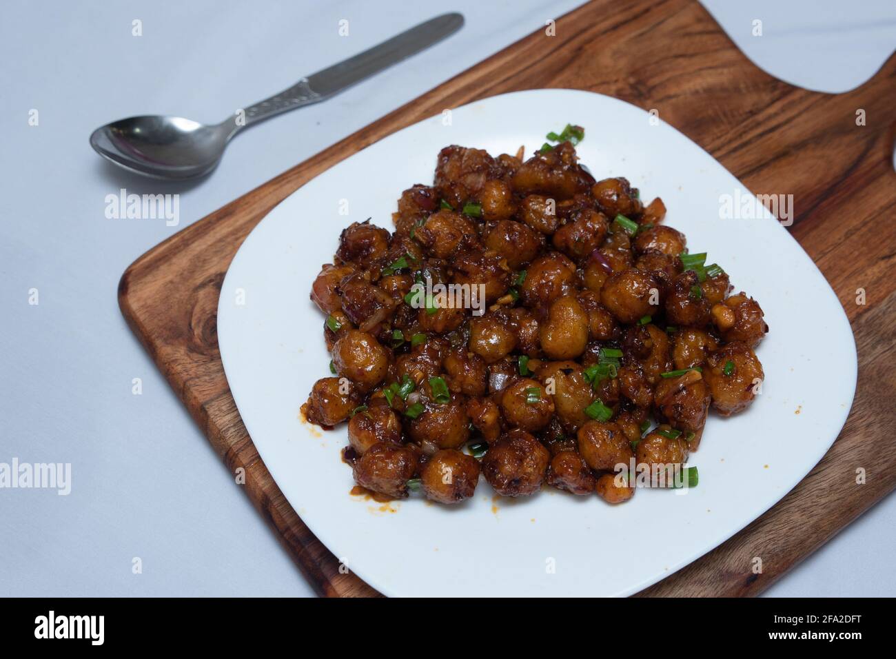 Plate of delicious fried crispy chilli baby corn on a wooden board ...