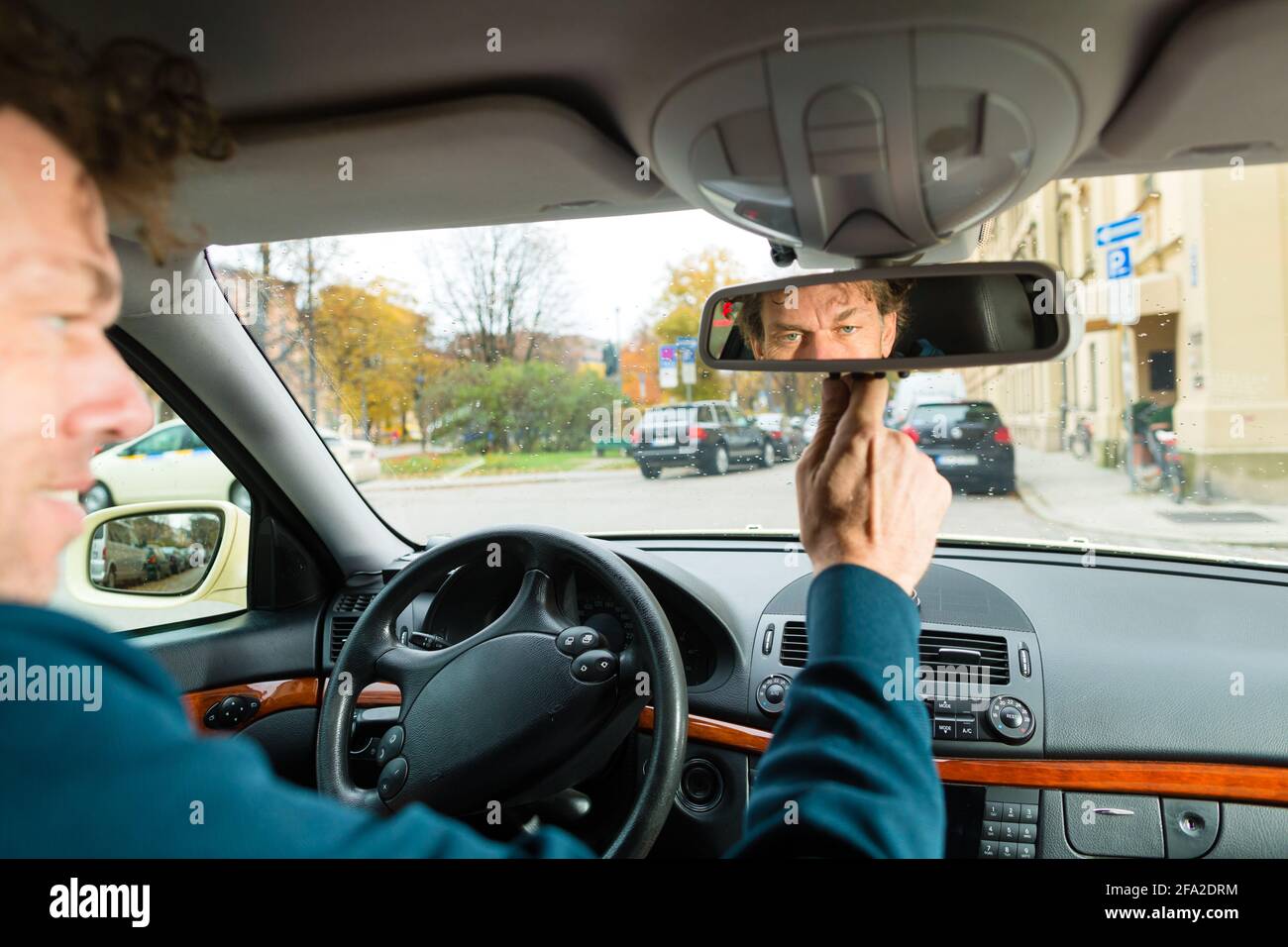 Experienced taxi driver is looking in the rear view mirror in his taxi ...