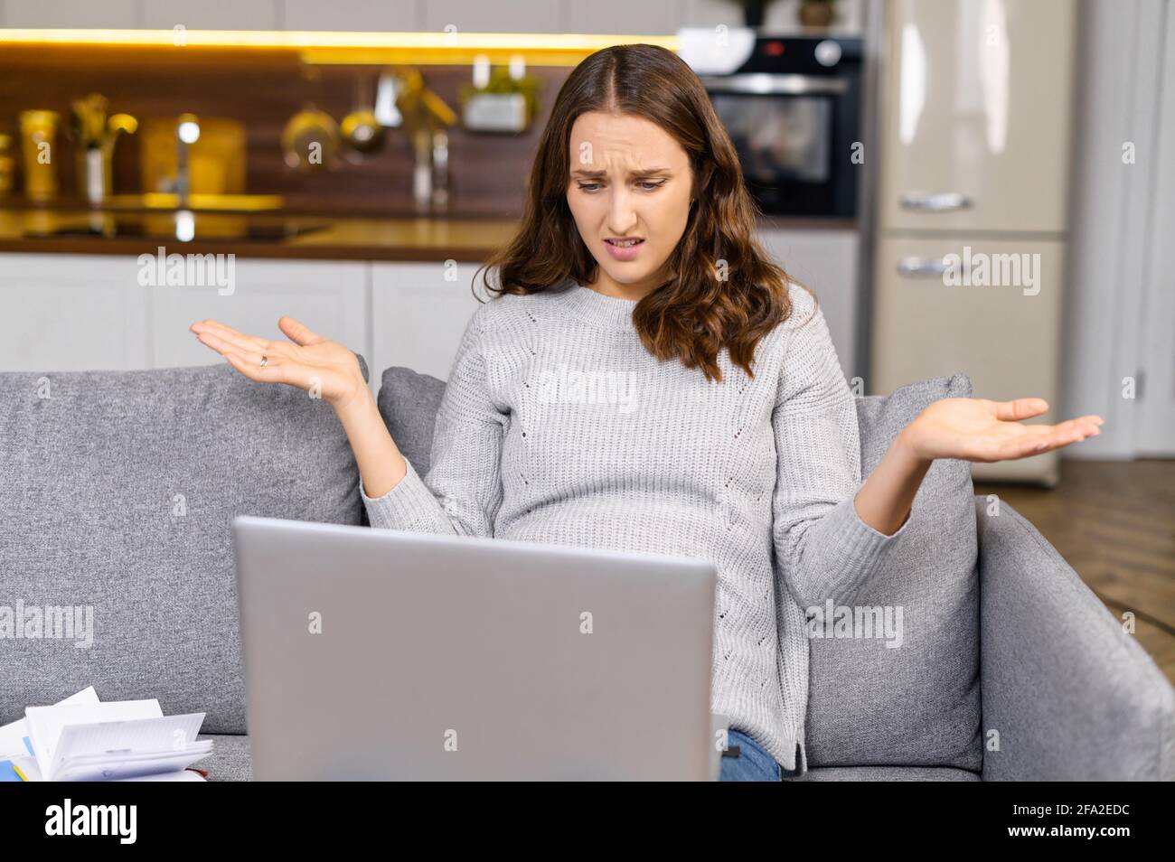 Confused female entrepreneur sits on the couch and staring at the ...